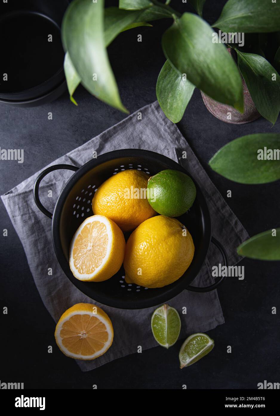 juicy lemons and limes in a black bowl on a gray table. Dark and mood ...