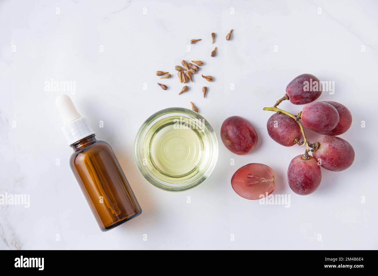 Flat lay is made of natural grape seed oil on white marble background ...