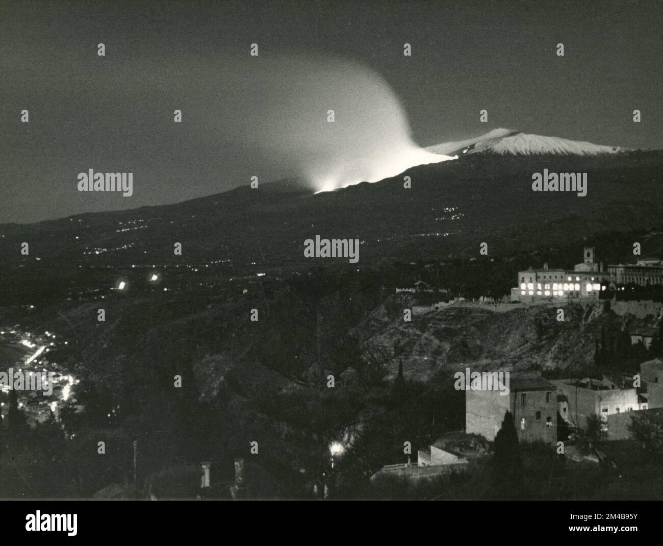 View of Taormina and Etna Volcano by night, Italy, 1950s Stock Photo ...