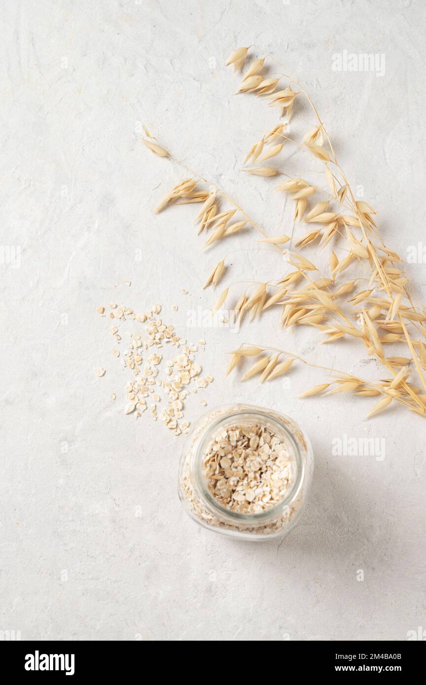 oat flakes in a jar with oats dry brunch on a white textured background ...