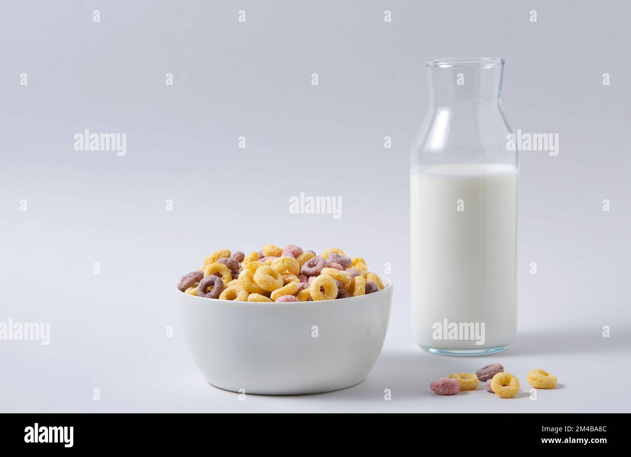 sweet colorful cornflakes rings in a white bowl with a bottle of milk ...