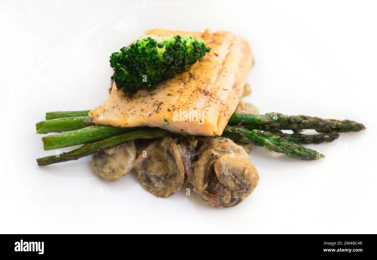 dish of fried river trout fillet with garnish of broccoli, asparagus ...