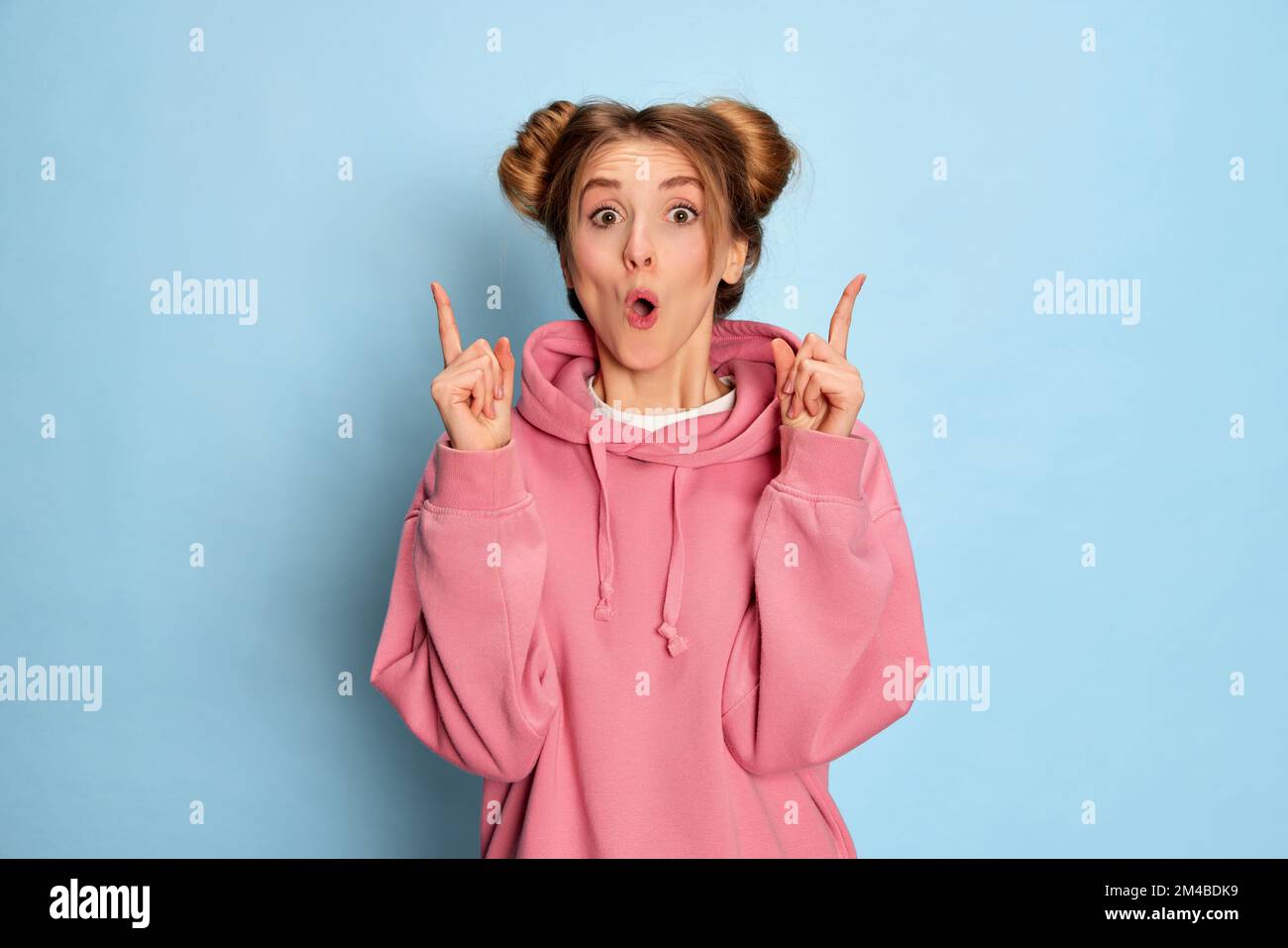 Portrait of young emotive girl in pink hoodie posing with excited face ...