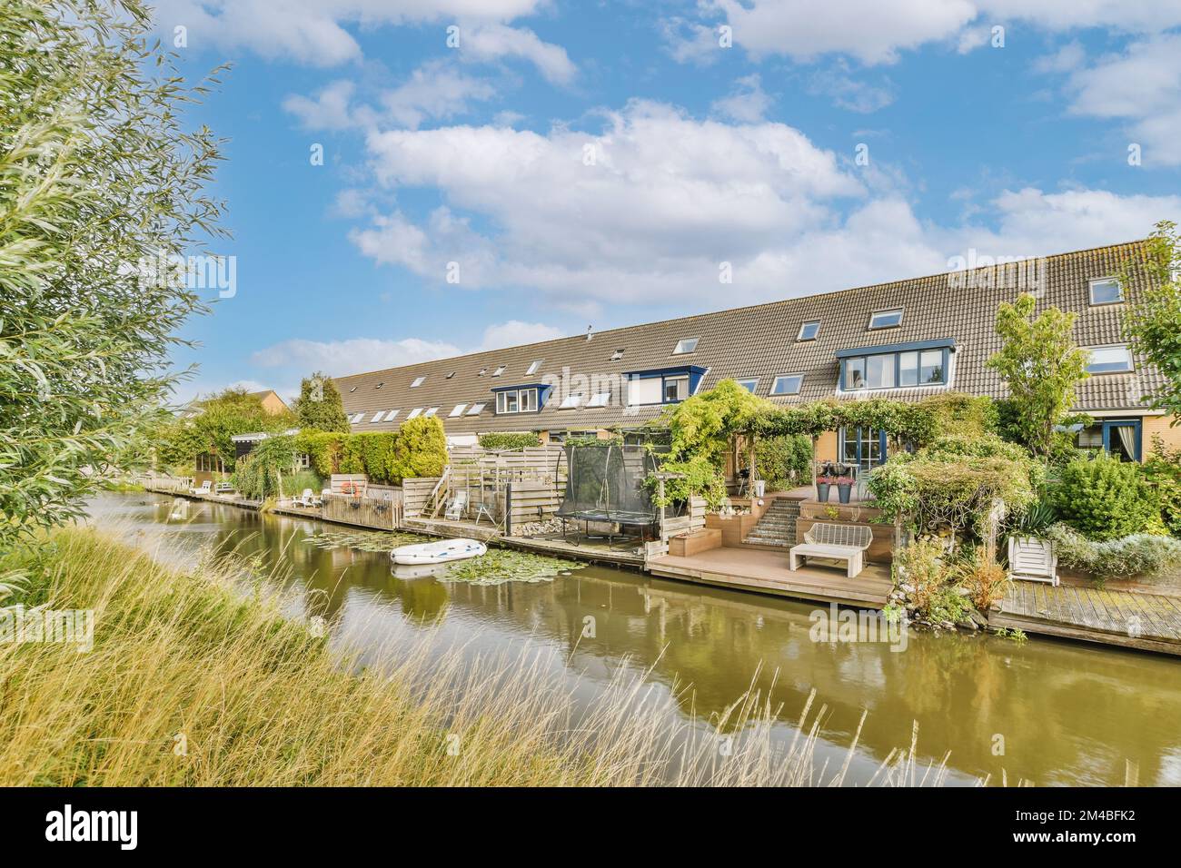 some houses on the side of a body of water with trees and bushes in the ...