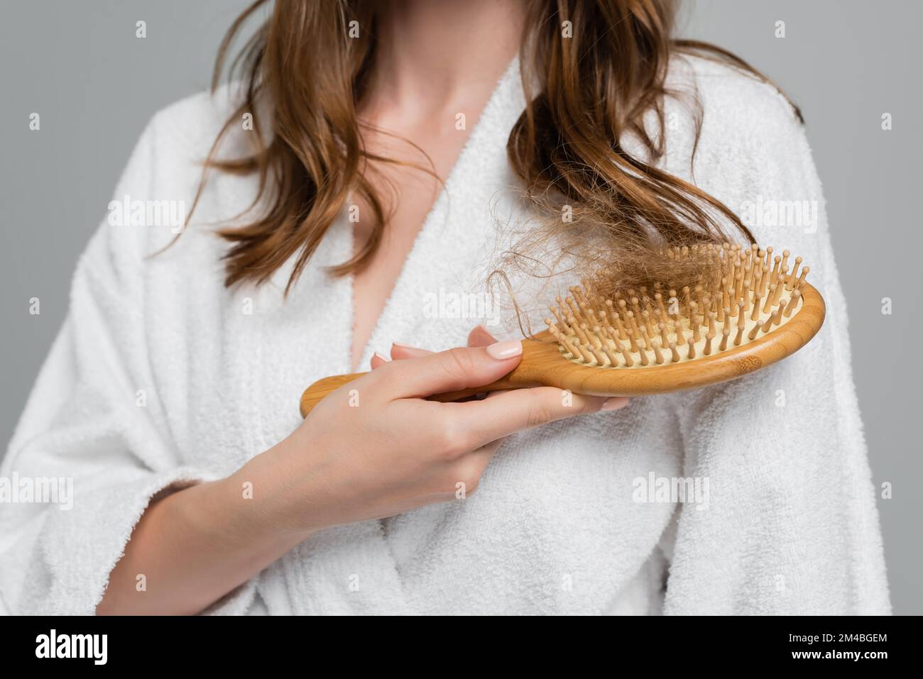 partial view of young woman holding wooden hair brush with damaged hair ...