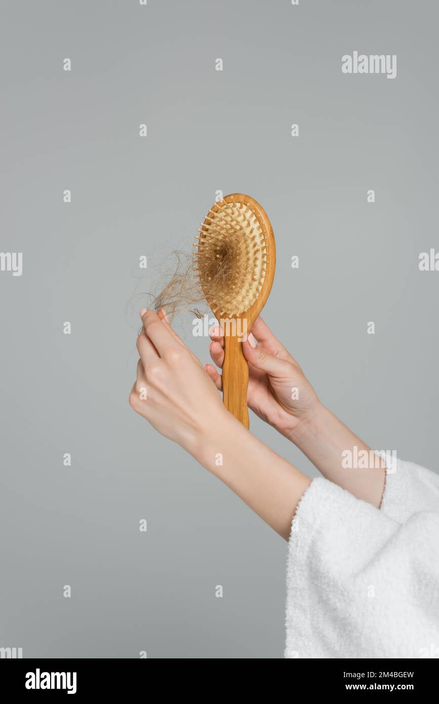 partial view of young woman holding wooden hair brush and pulling ...