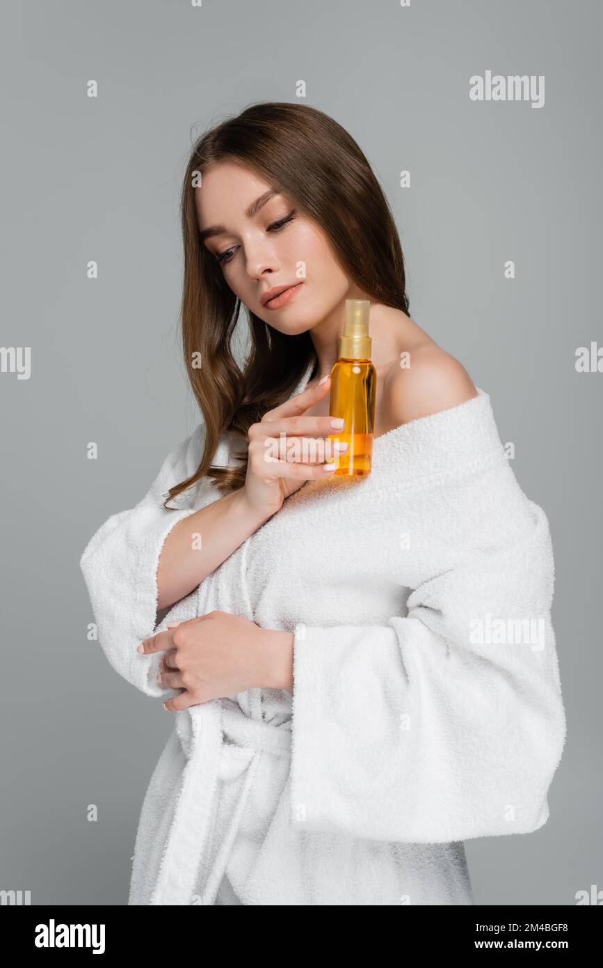 brunette young woman with shiny hair holding bottle with oil isolated ...
