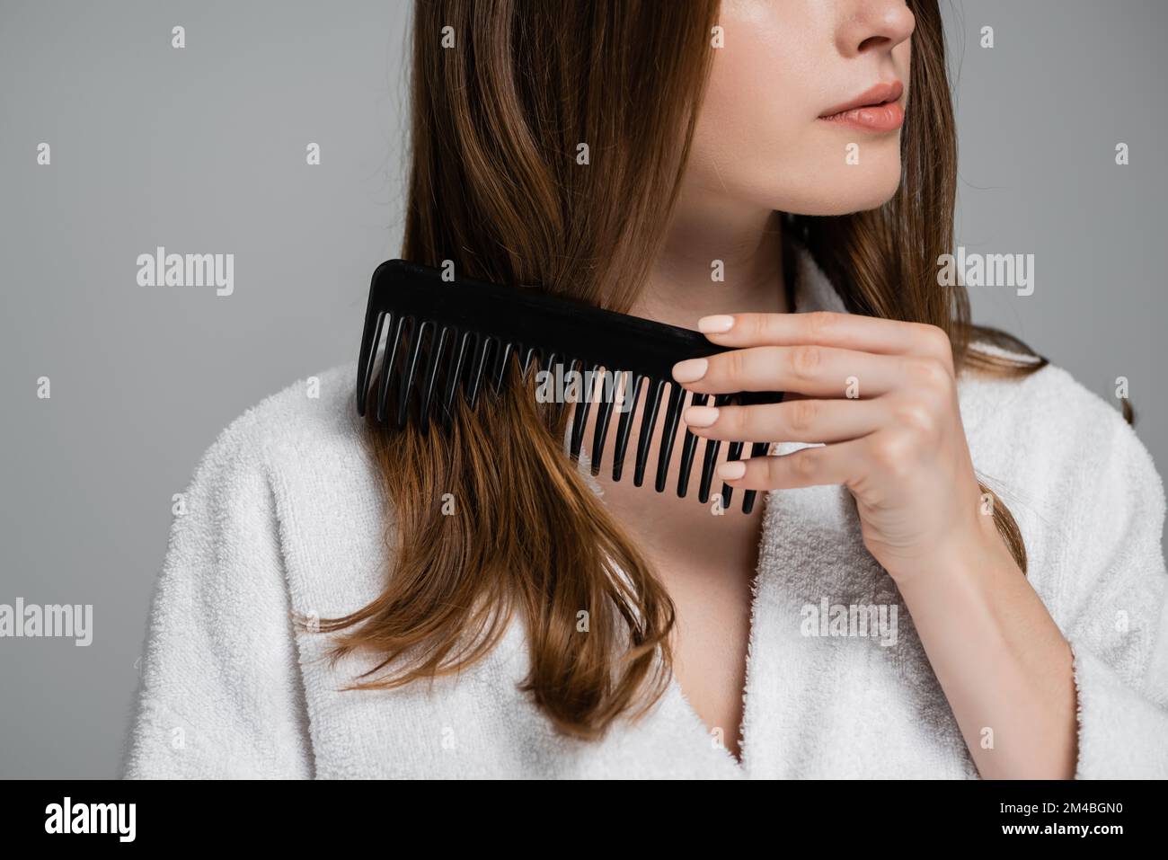 partial view of young woman brushing shiny and healthy hair with ...
