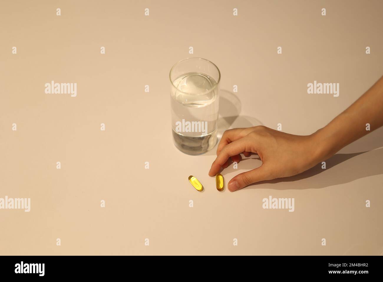 Woman is taking medicine with cup of water on the white table, girl is ...