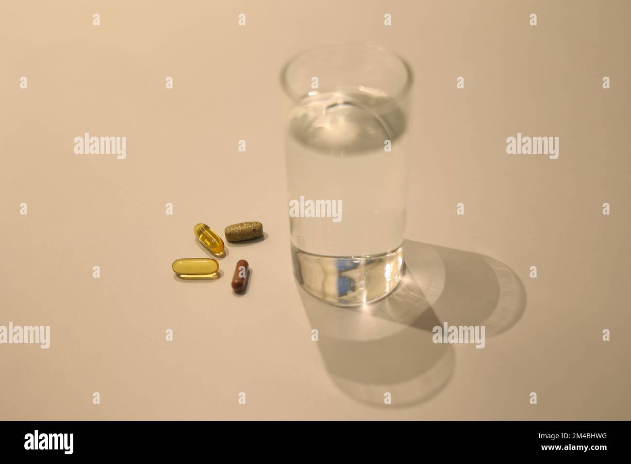 Many kinds of medicine and cup of water on the white table, nutritional ...