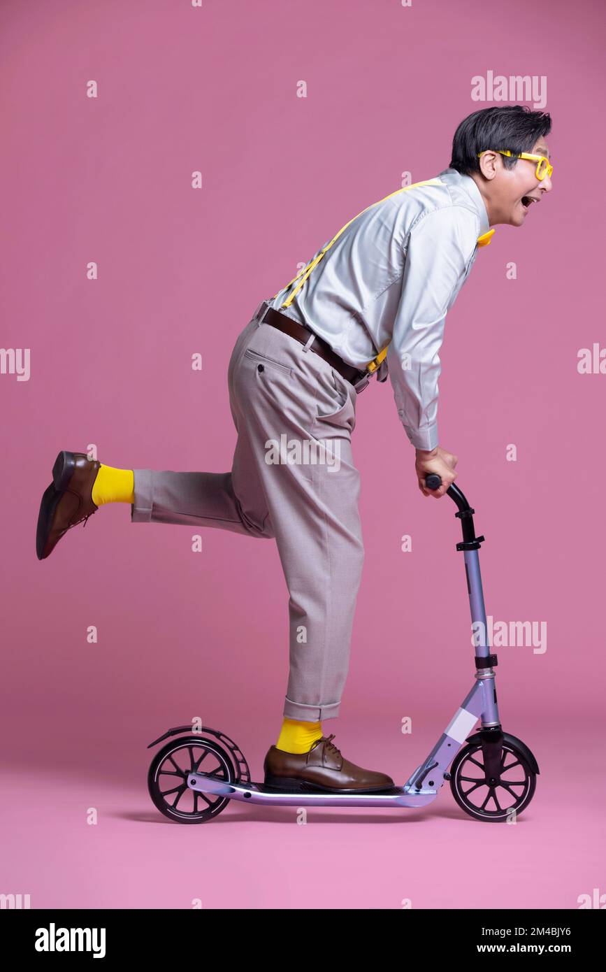 Cheerful senior Chinese man riding scooter Stock Photo - Alamy