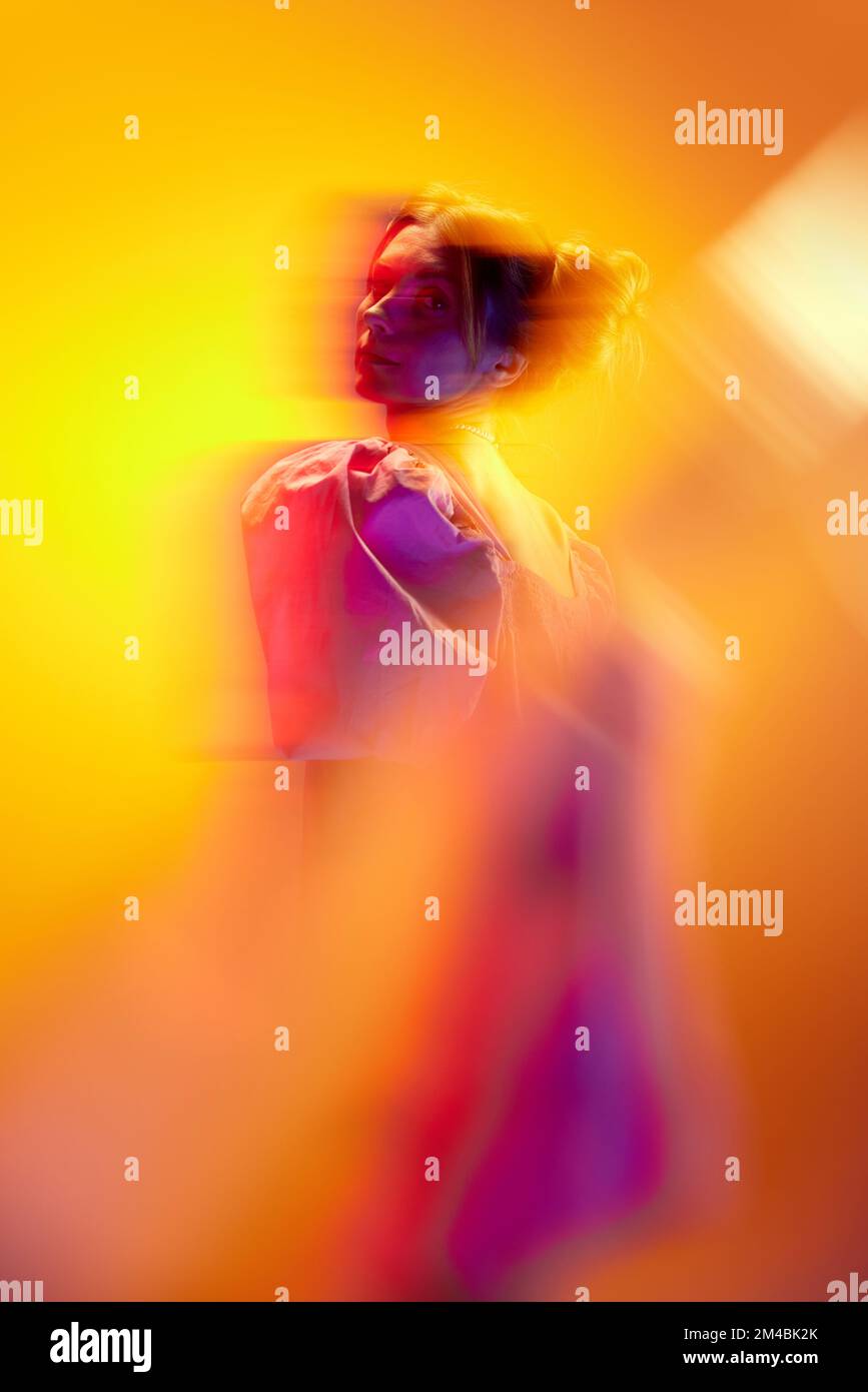 Portrait of young beautiful girl in white dress posing over orange ...