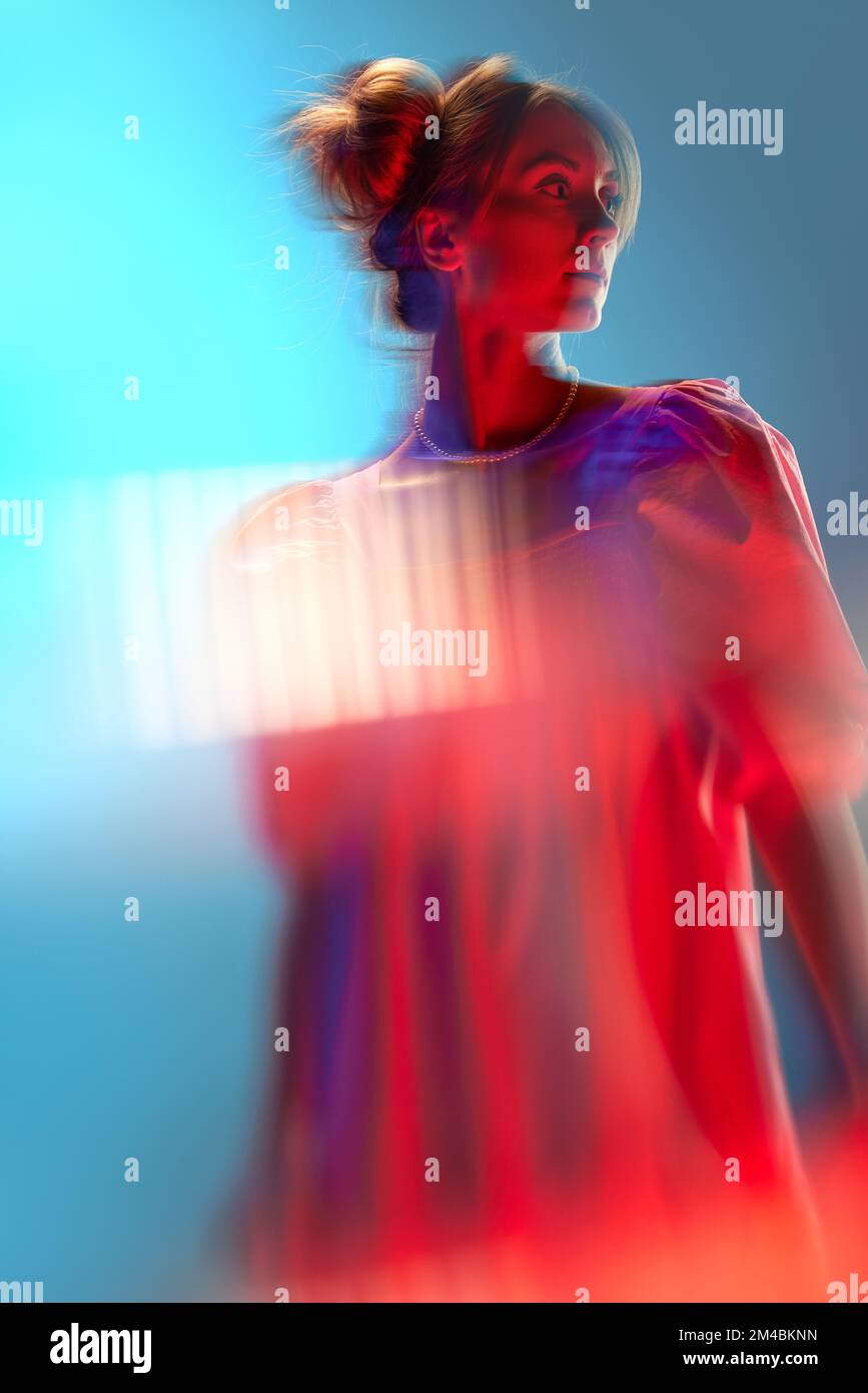 Portrait of young lovely girl in white dress posing over blue ...