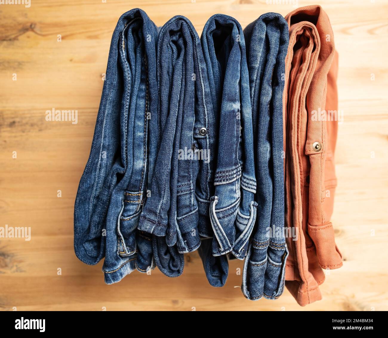 Jeans neatly folded in a pile on a wooden shelf. Flatley. Concept of ...