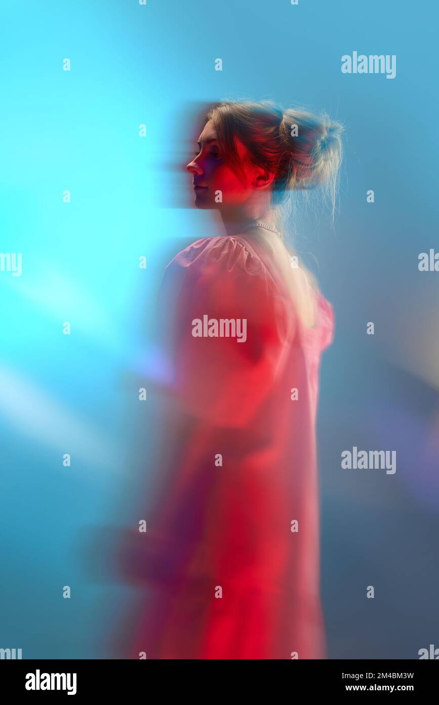 Portrait of young beautiful girl in white dress posing over blue ...