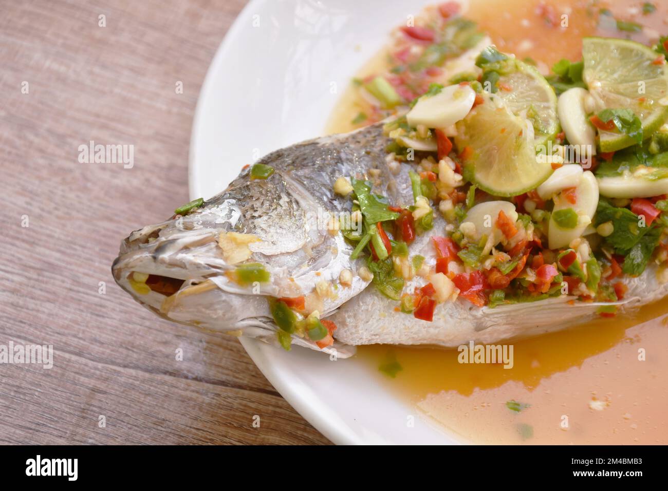 steamed bass fish dressing lemon sweet and sour chili sauce on plate ...