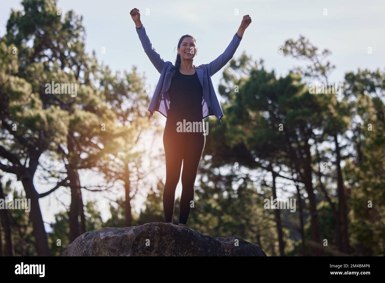 Hiking, winning and woman celebrating on a rock in a forest for fitness ...