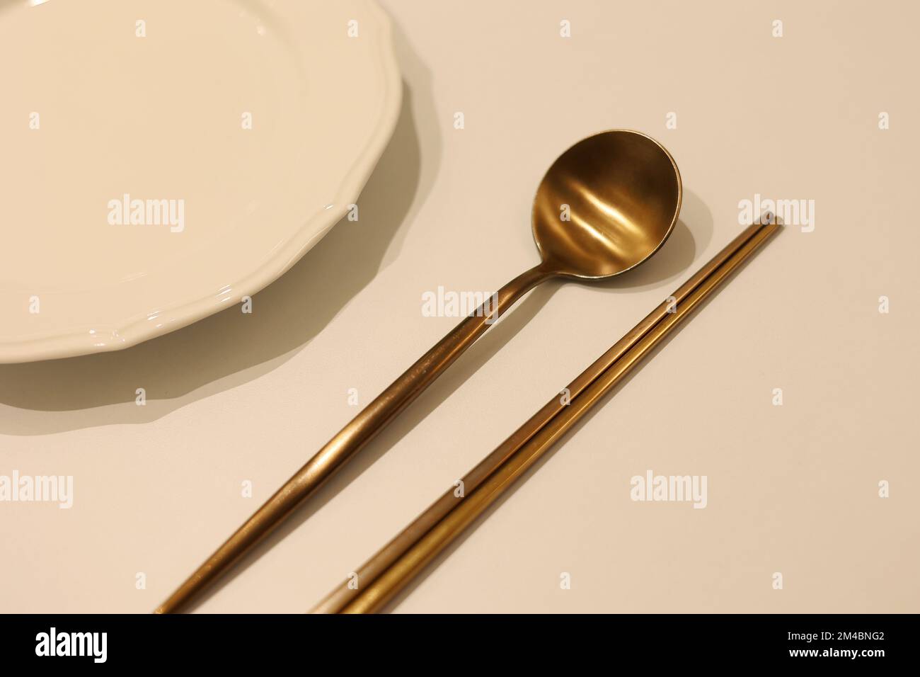 A set of Korean brass spoon and chopstick with empty white dish on the ...