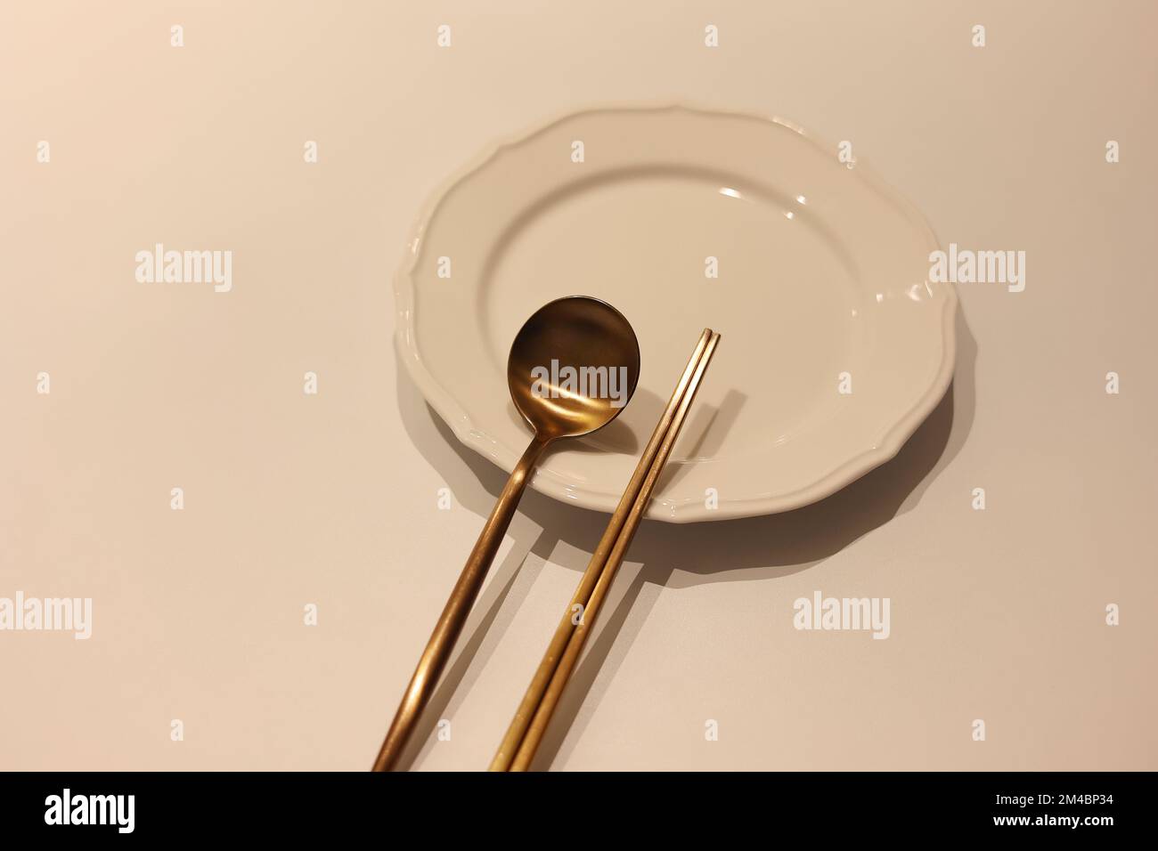 A set of Korean brass spoon and chopstick with empty white dish on the ...