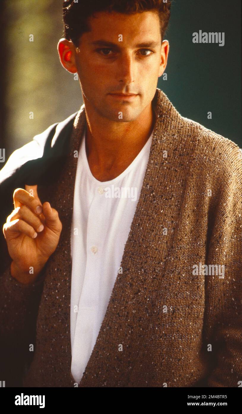 White Male Model In A Sweater Posing For A Picture While Holding His Jacket Over His Shoulder