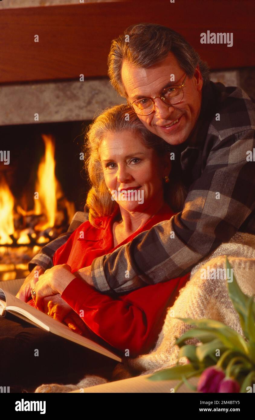 Older couple embracing and pausing to look at the camera while sitting ...