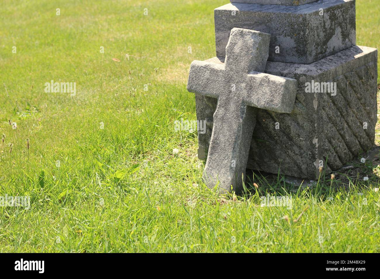 An old stone cross leaning against a tombstone Stock Photo - Alamy