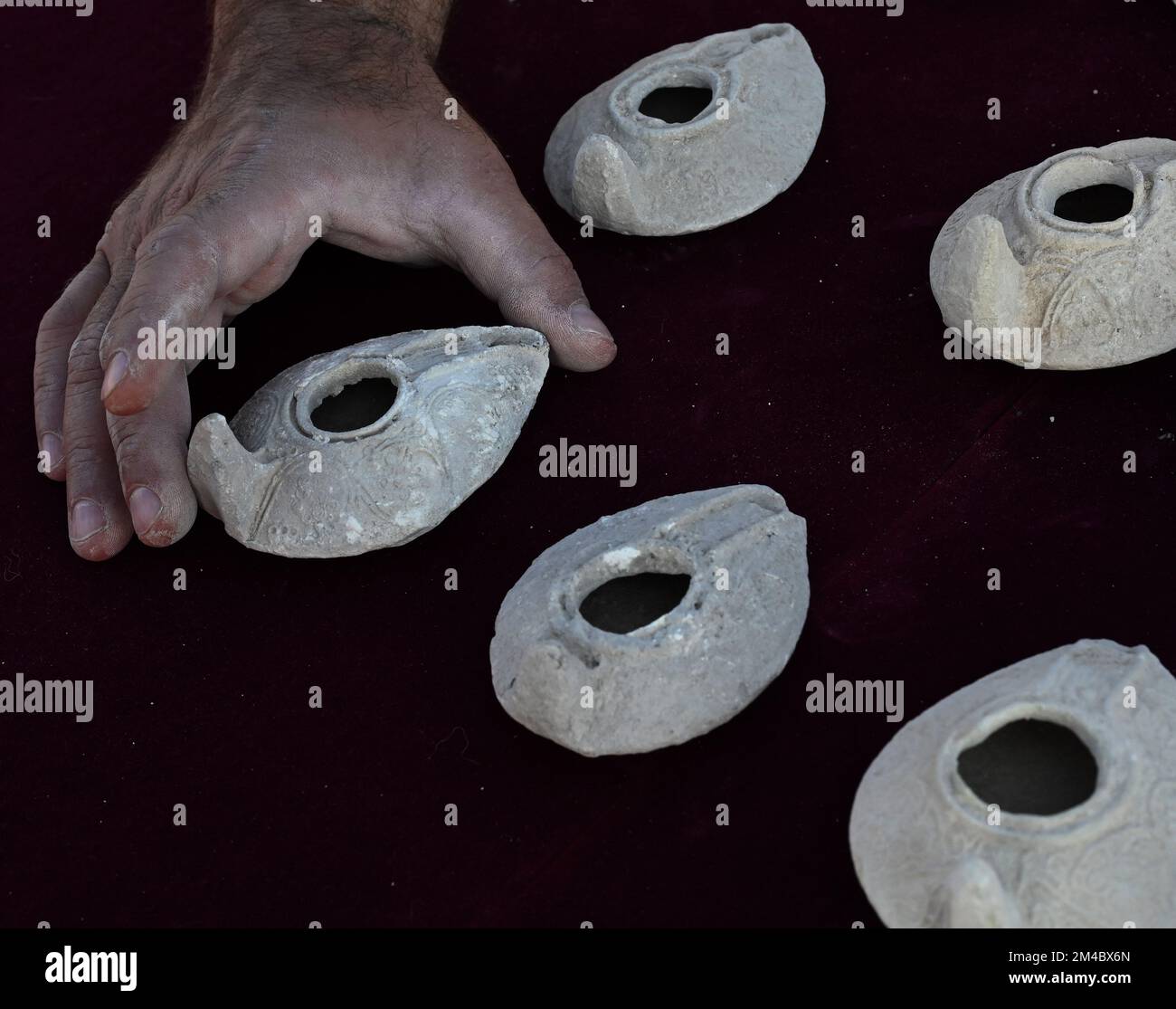 An archeologist from The Israel Antiquities Authority holds a clay lamp ...
