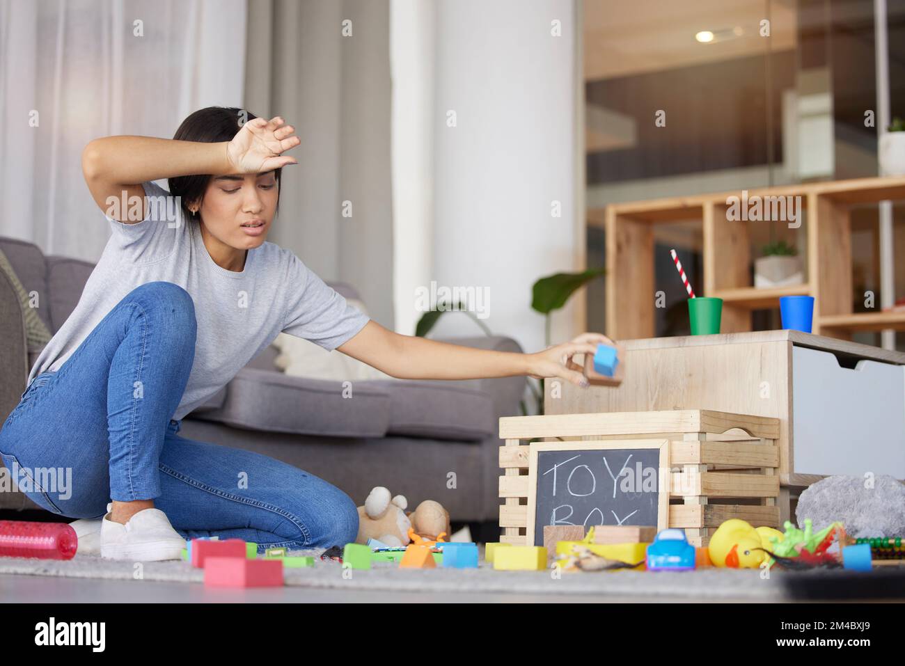 Toys, mother tired and headache for cleaning, messy living room and ...