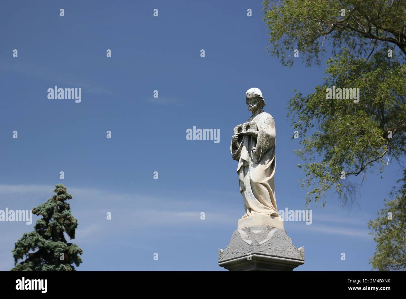 Beautiful stone statue of St Joseph standing against a clear blue sky ...