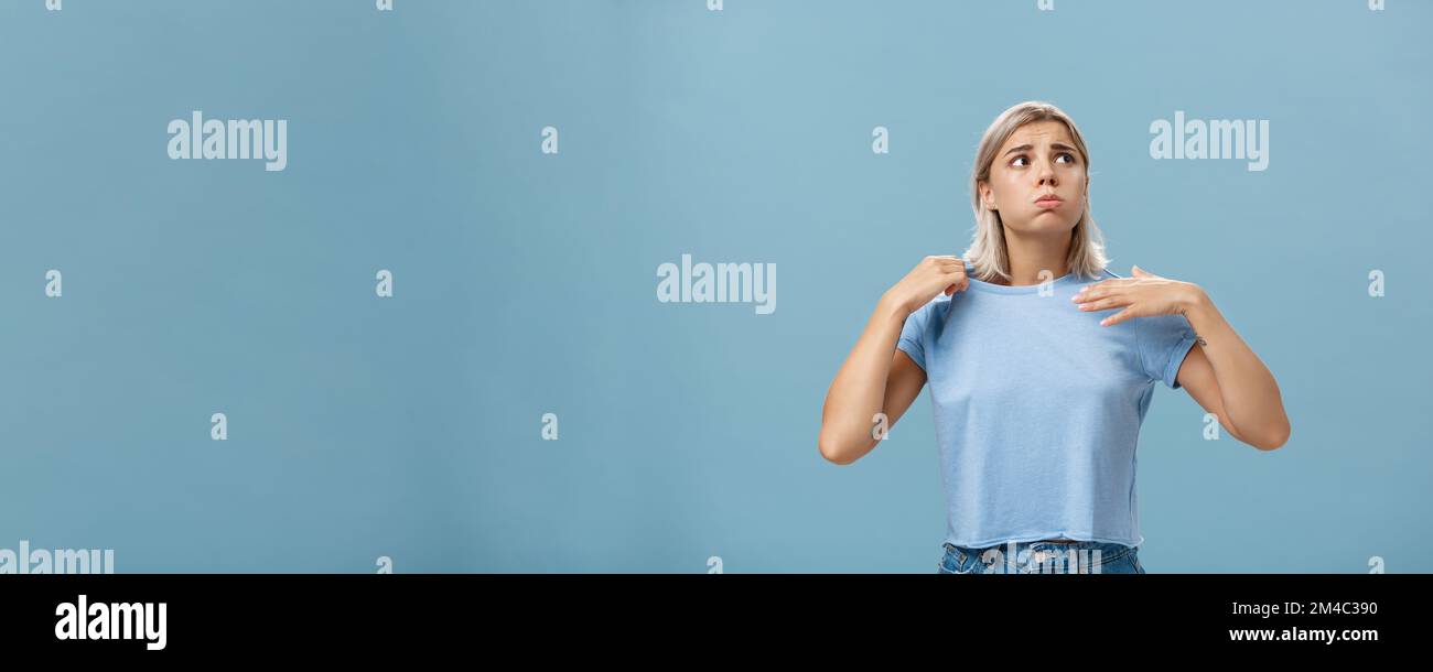 Girl feeling discomfort from heat standing over blue background in fug ...