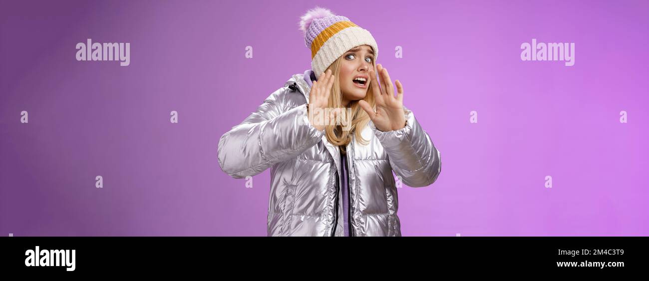 Afraid intense uncomfortable young fair-haired woman in winter hat ...