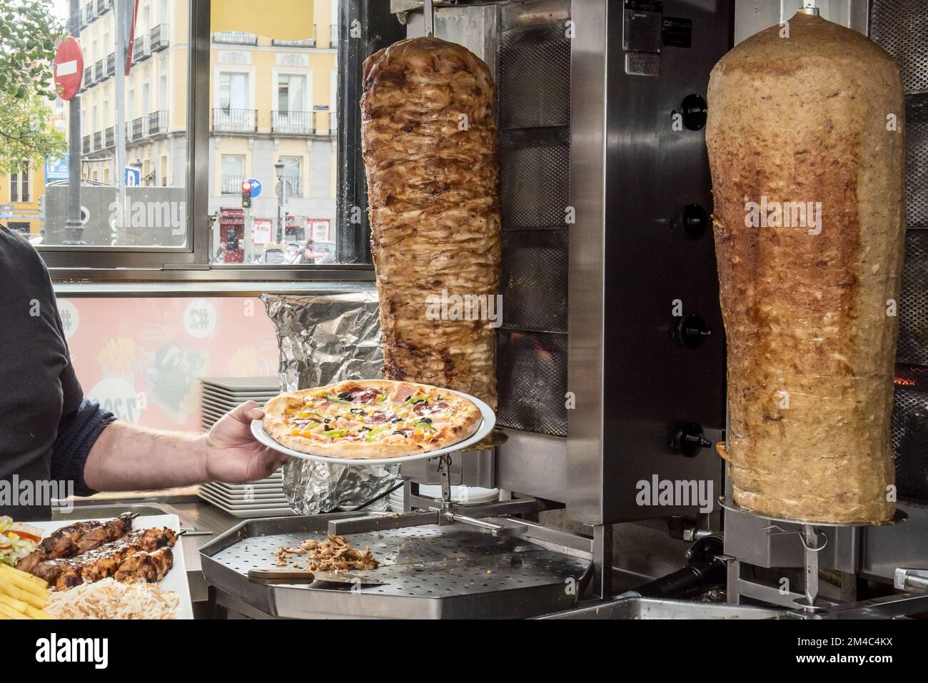 Upright rotating kebab skewers, pizzas and other food cooked on the ...