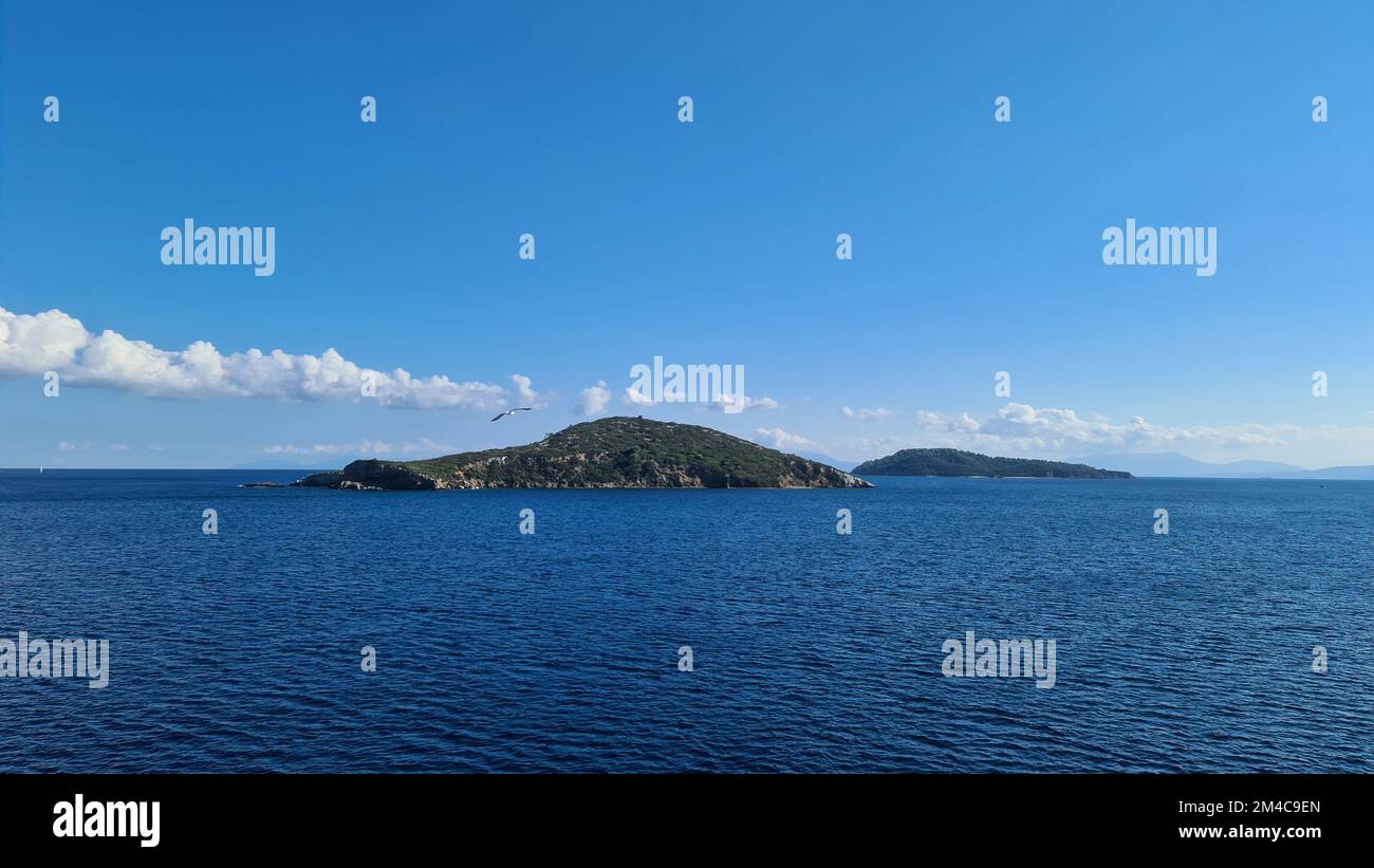 A scenic view of a vast blue ocean with green mountains in the ...