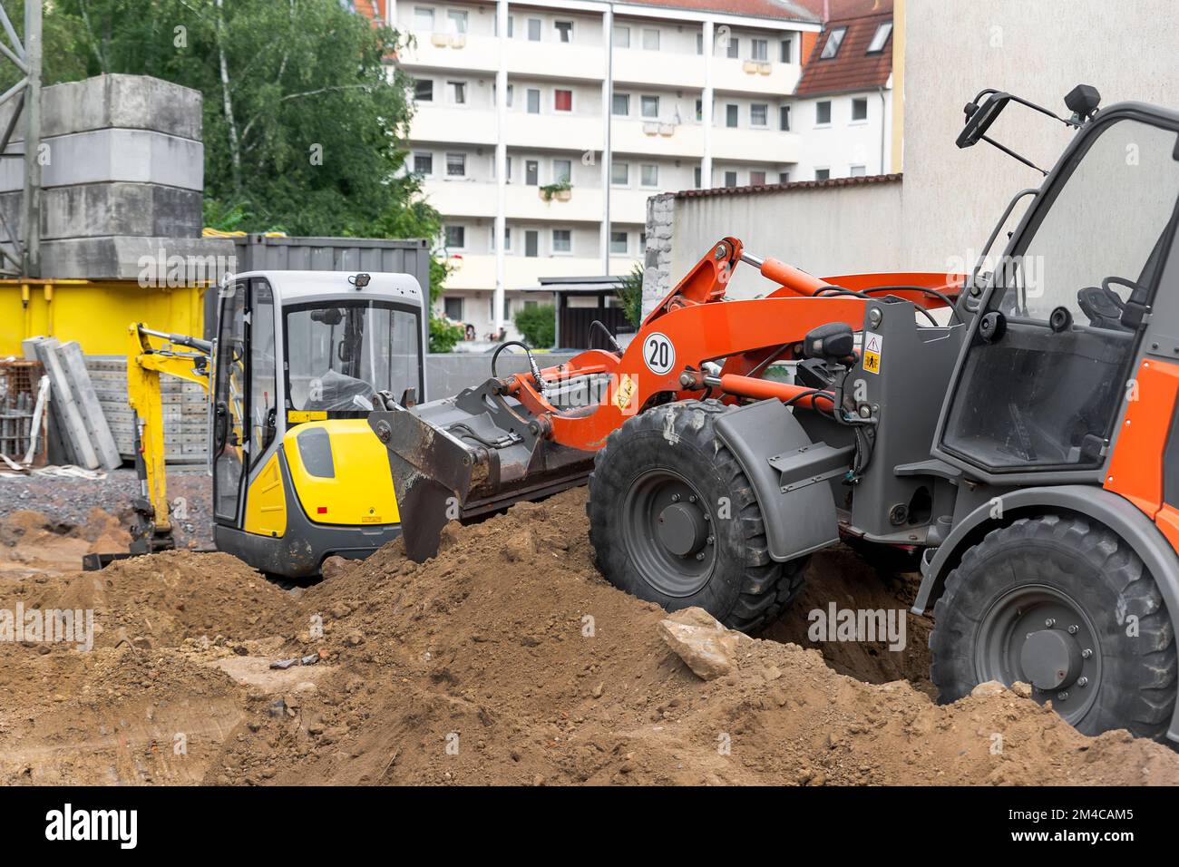 Small loader and excavator digger machine moving heap of earth and ...