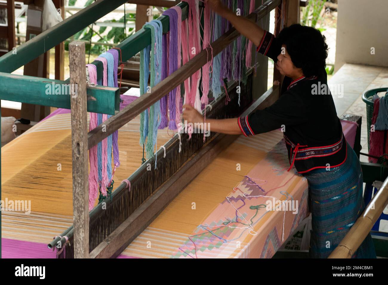 An unidentified Lua or H'Tin Hill Tribe woman is weaving by loom on a ...
