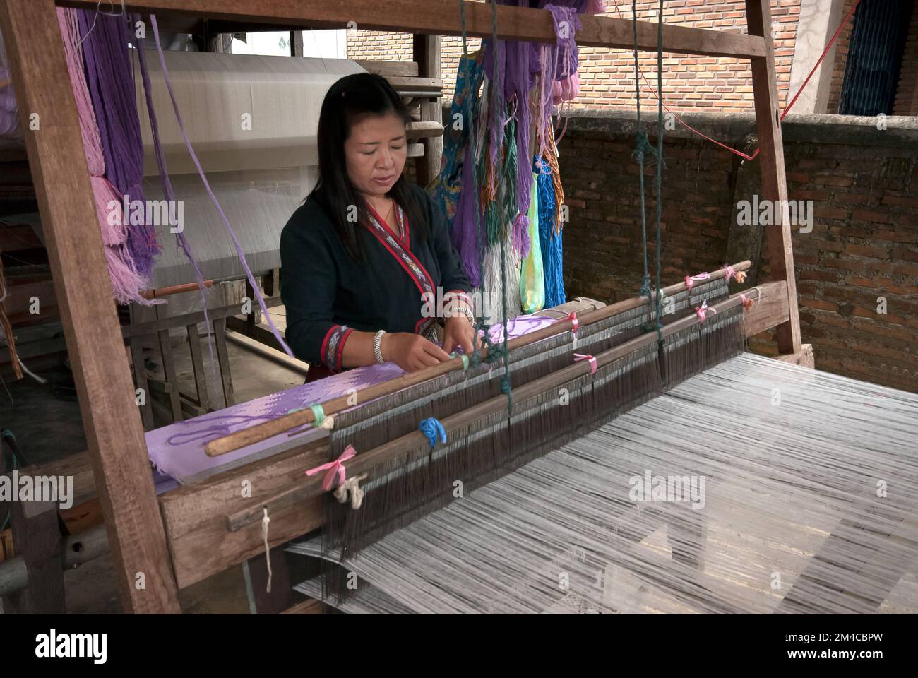An unidentified Lua or H'Tin Hill Tribe woman is weaving by loom on a ...