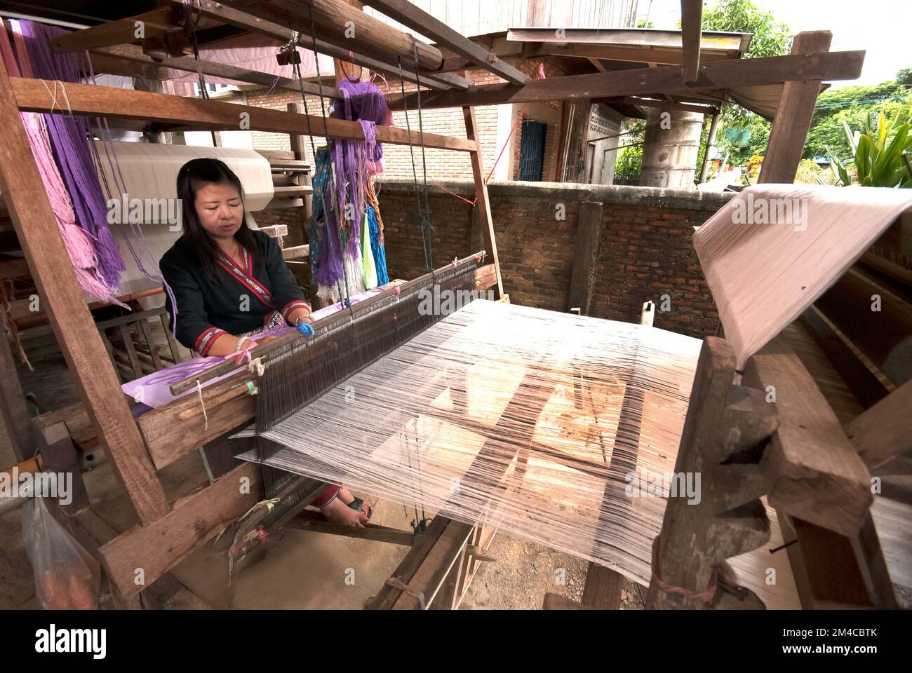 An unidentified Lua or H'Tin Hill Tribe woman is weaving by loom on a ...