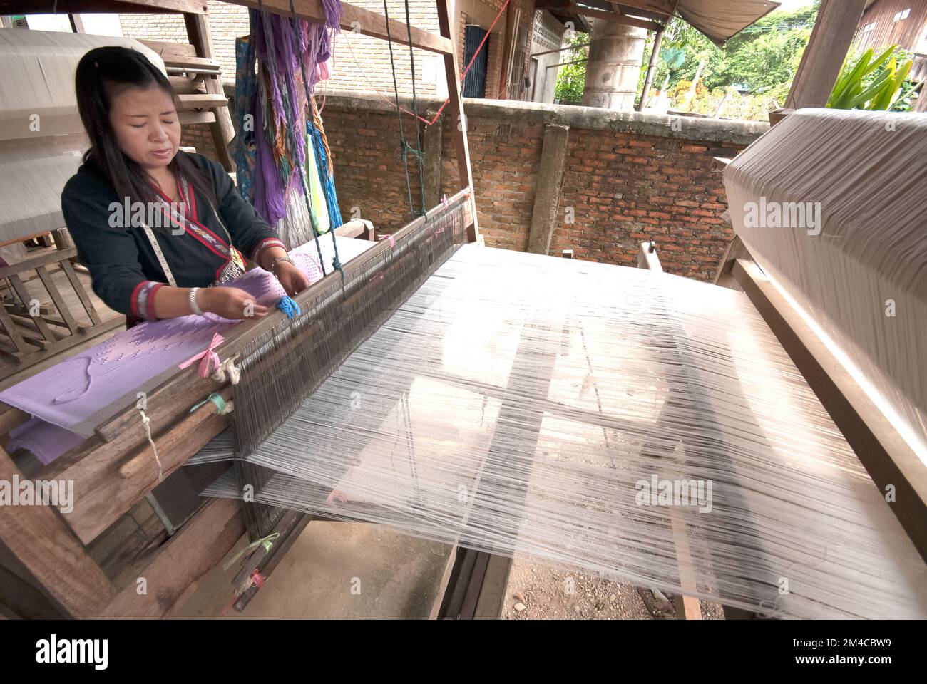 An unidentified Lua or H'Tin Hill Tribe woman is weaving by loom on a ...