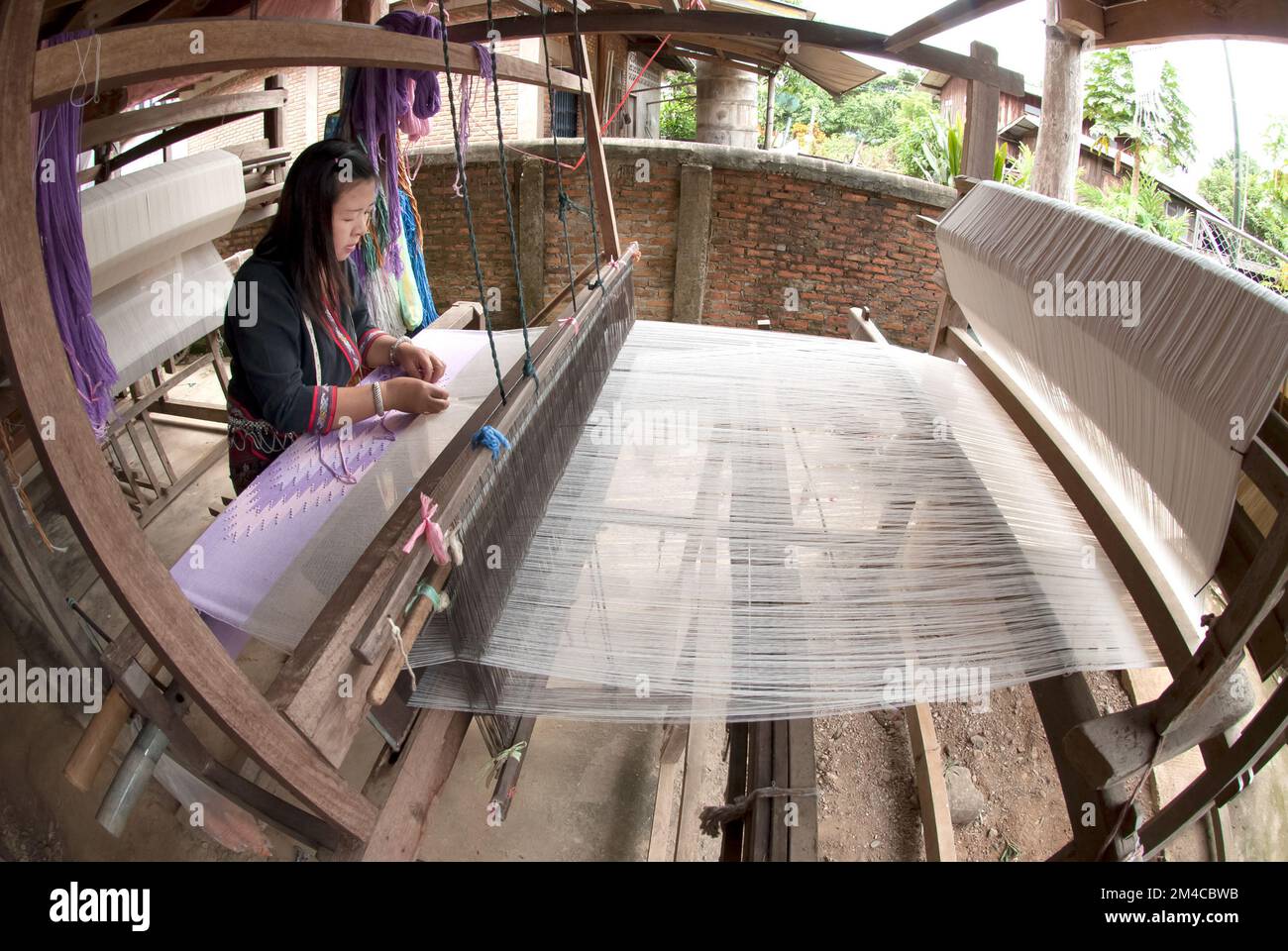 An unidentified Lua or H'Tin Hill Tribe woman is weaving by loom on a ...