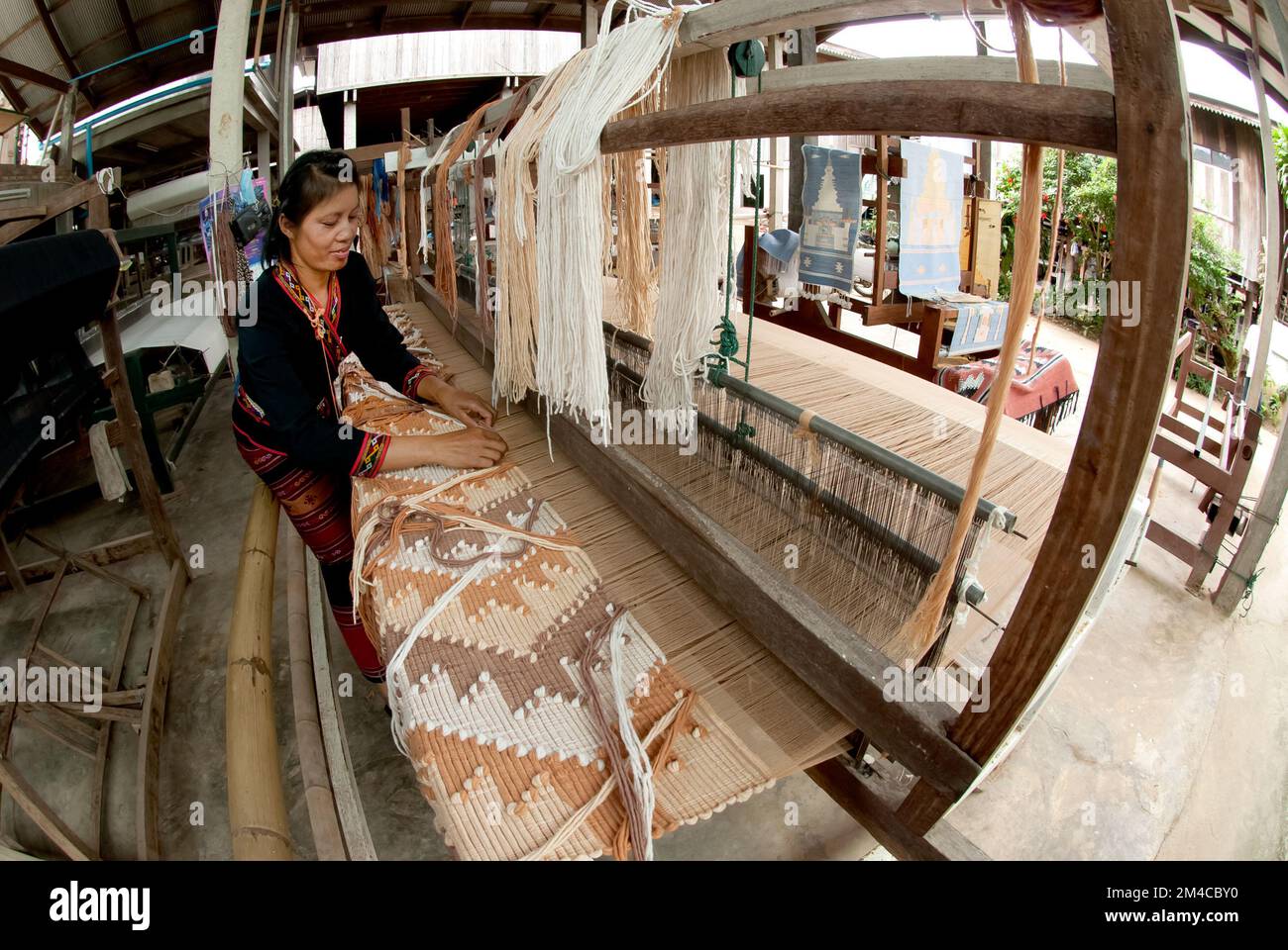 An unidentified Lua or H'Tin Hill Tribe woman is weaving by loom on a ...