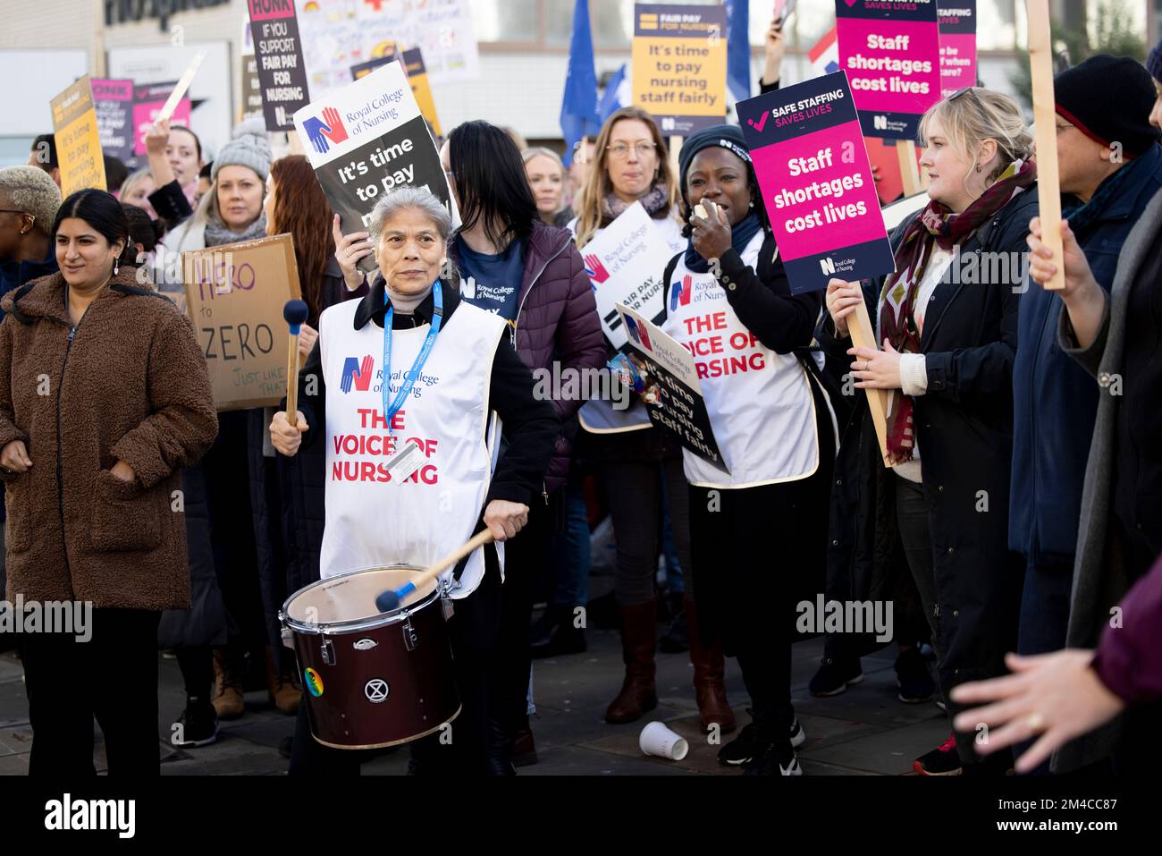 London, UK. 20th Dec, 2022. Protesters march with a drum and placards ...