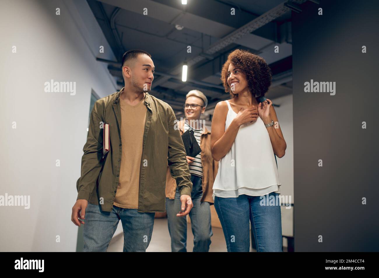 Cheerful company employee flirting with her coworker in the hallway ...