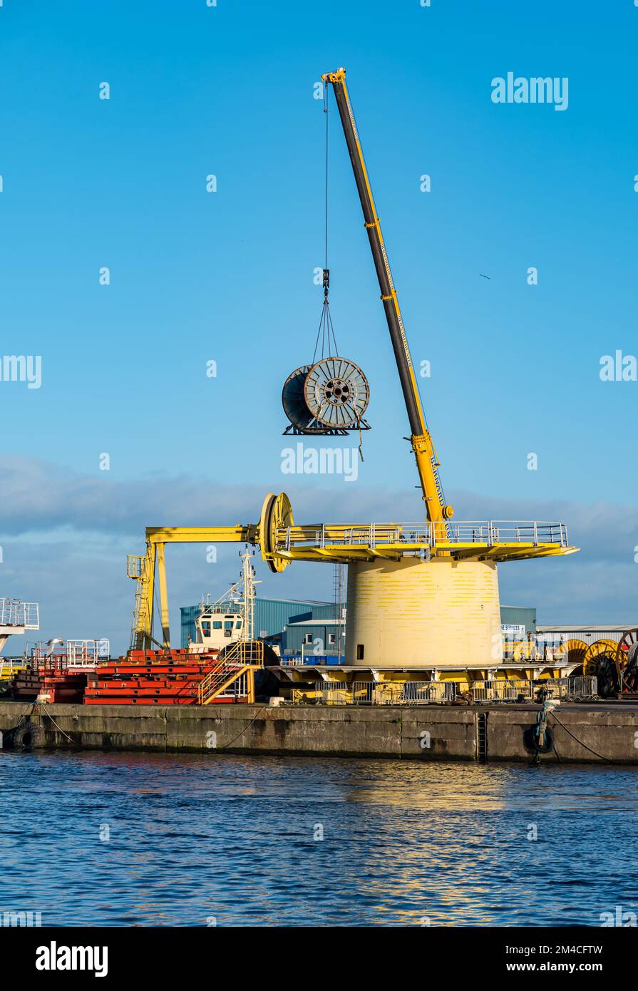 Industrial crane lifting cable wheel on dockside, Leith Docks ...