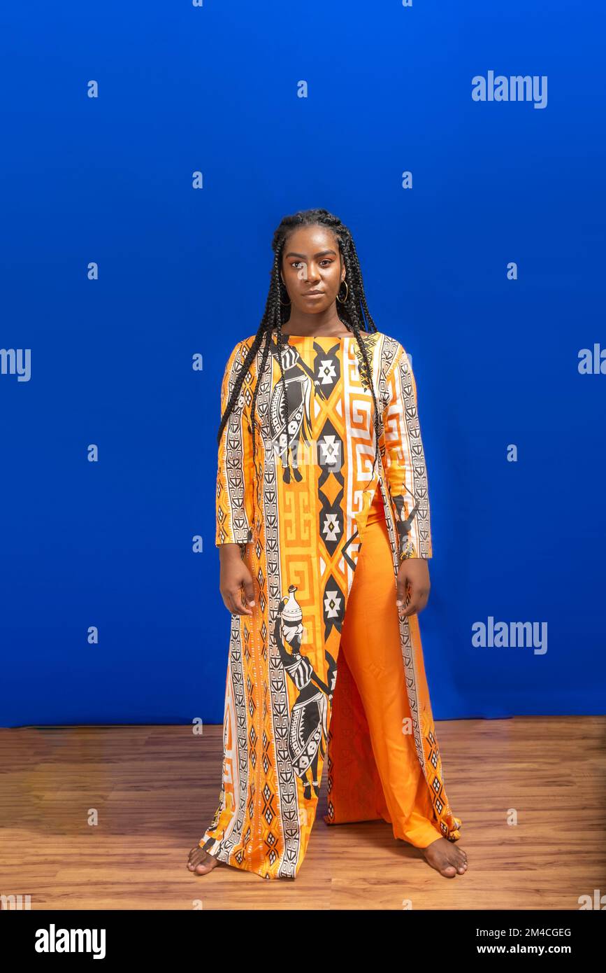 Young woman wearing colorful long clothes over blue background. Natural ...