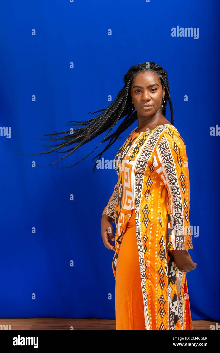Young woman wearing colorful long clothes over blue background. Natural ...