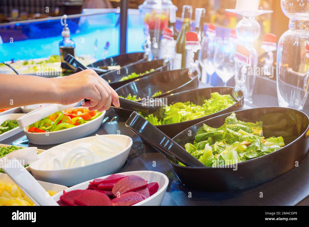Asian woman choosing vegetable ingredients at salad bar buffet ...