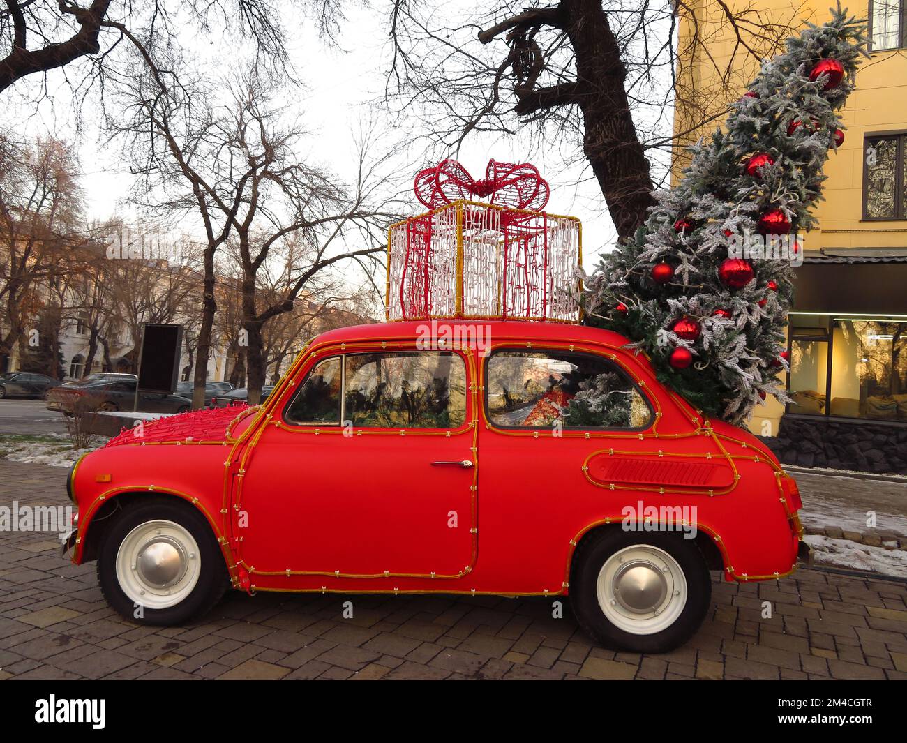 Red retro car with Christmas tree decorations and a Christmas tree in ...