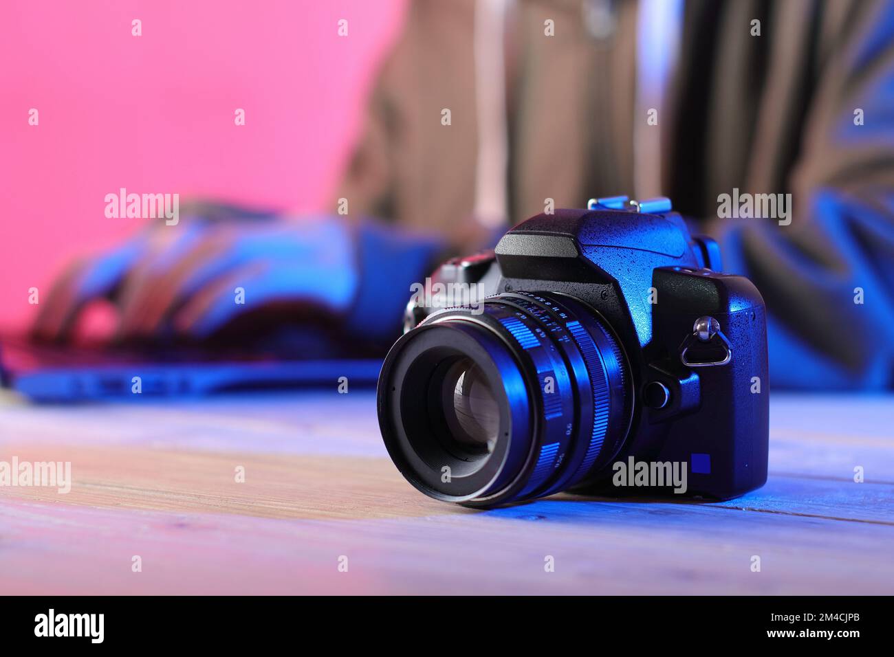 digital slr camera with old lens on table with person and colored ...