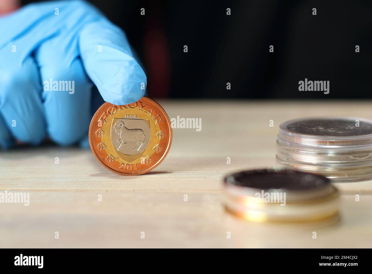 colored coin under the finger on the table vertically and background of ...