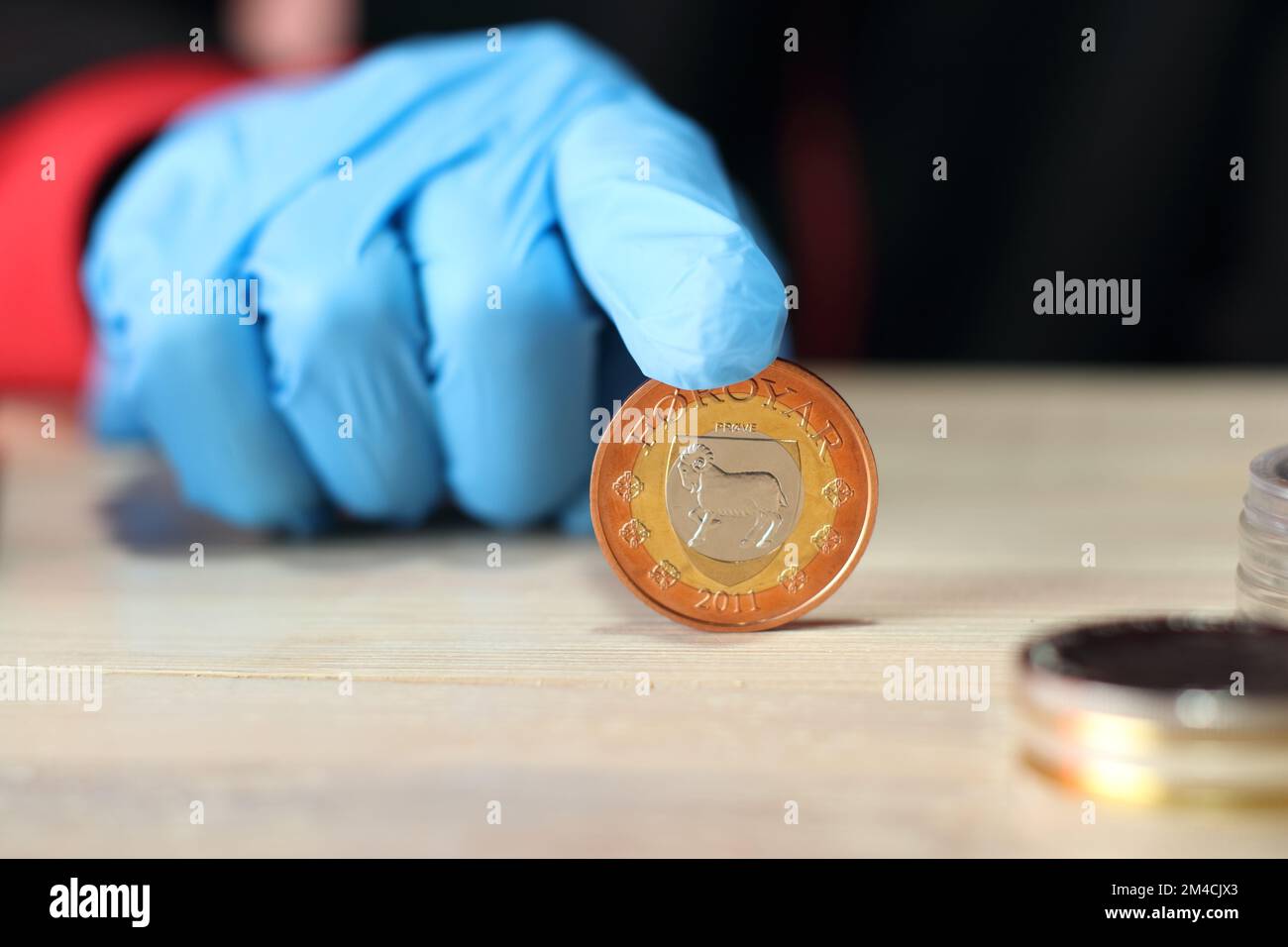 colored coin under the finger on the table vertically and background of ...
